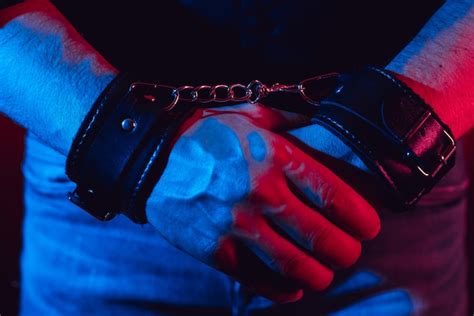 Premium Photo A Man Hands Wearing A Pair Of Black Leather Handcuffs
