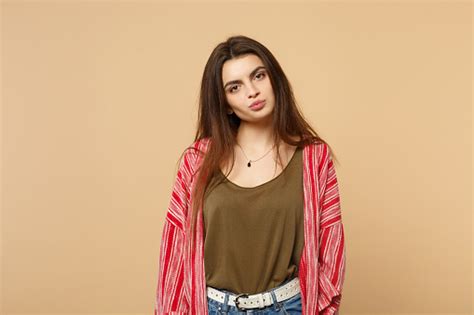 캐주얼 서 서와 스튜디오에서 파스텔 베이 지 배경에 고립 된 찾고 카메라를 보고 잠겨있는 불쾌 한 젊은 여자의 초상화 사람들은