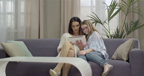 Mom With Her Daughter And Son In The Living Room Relaxing With A Tablet