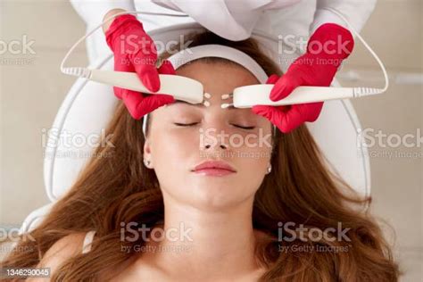 치료사로부터 자극 전기 얼굴 치료를받고 스파 클리닉에서 아름다운 여자 미세 전류 치료 중 젊은 여성 얼굴의 클로즈업 사람 얼굴에