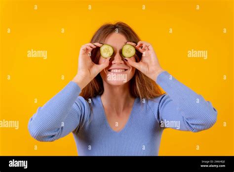 Vegan Woman With Cucumber Slices On Her Eyes On A Yellow Background