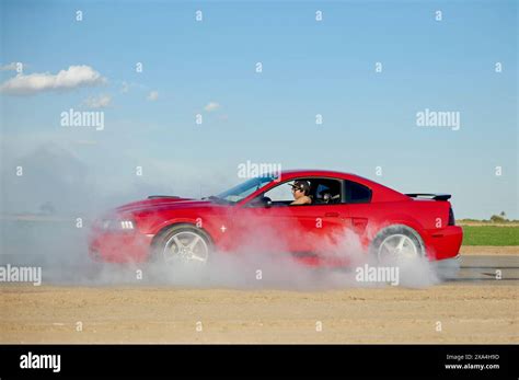 A Red Sports Car Is Performing A Burnout With White Tire Smoke Billowing From The Rear Tires