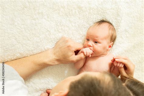 Cute Naked Newborn Baby With Open Eyes Lying On A Bed A Parent Holds