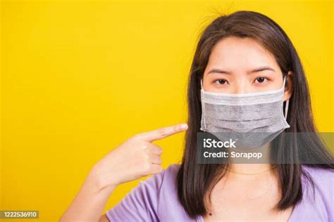 아시아 젊은 십대 여성은 코로나 바이러스에 대한 수술 위생 보호 얼굴 마스크를 착용하고 얼굴에 마스크를 가리키는 손가락 스튜디오