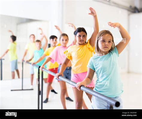 Focused Tween Girl Practicing Ballet Positions Near Bar During Group
