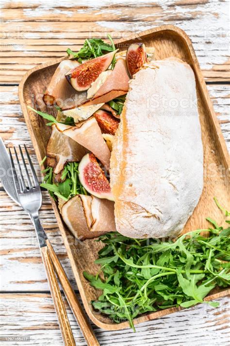 나무 트레이에 아루굴라 무화과 프로슈토 시아바타 블루 치즈를 곁들인 샌드위치 흰색 배경입니다 위쪽 보기 건강한 식생활에 대한