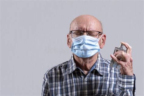 Old Bald Man With Glasses And Medical Mask With Perfume Bottle Spray In