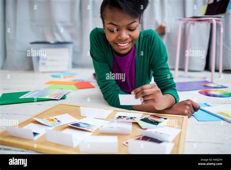 Girl Lying On The Floor Of Design Studio And Looking Through Photos Stock Photo Alamy