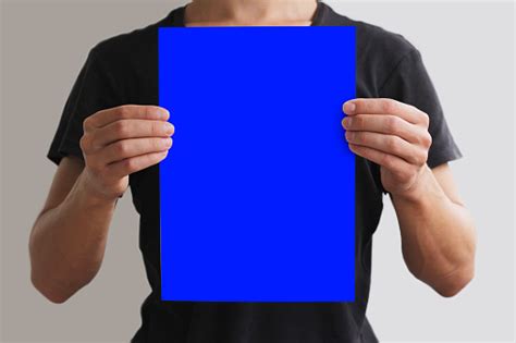 검은 색 티셔츠를 입은 남자가 파란색 A4 용지를 수직으로 들고 있습니다 전단지 프리젠 테이션 팜플렛이 손을 잡습니다 남자는 명확한 오프셋 종이를 보여줍니다 시트 템플릿