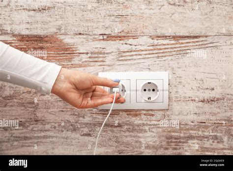 Woman Inserting Plug Into Socket On Wooden Wall Stock Photo Alamy