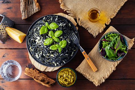 파마산 치즈 바질 페스토 소스를 곁들인 파스타 스파게티 블랙 파스타 소스 페스토 신선한 채소 믹스 샐러드를 나무 판에 놓습니다 플랫 레이 위쪽 보기 갈색에 대한 스톡 사진