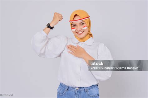 8월 17일 인도네시아 독립기념일을 축하하는 동안 히잡을 쓰고 경례하는 제스처를 보여주는 흥분한 젊은 아시아 무슬림 여성이 흰색 배경 위에 고립되어 있다 독립에 대한 스톡