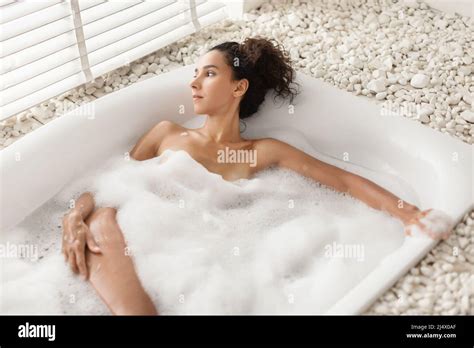 Dreamy Millennial Woman Relaxing In Hot Bubble Bath Looking Out Window