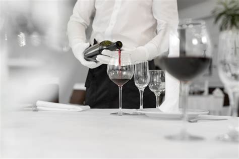 Premium Photo Male Waiter In White Gloves Pours Red Wine Into A Glass