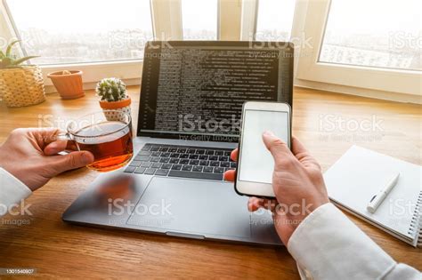 남자는 현대 기술 노트북 및 휴대 전화와 함께 작동합니다 아늑한 밝은 사무실에서 일하는 프로그래머 또는 사업가의 최고 전망