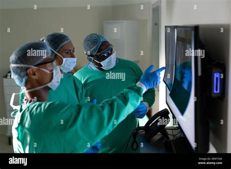 Diverse Male And Female Surgeons Looking At X Rays In Operating Theatre Before Surgery Stock