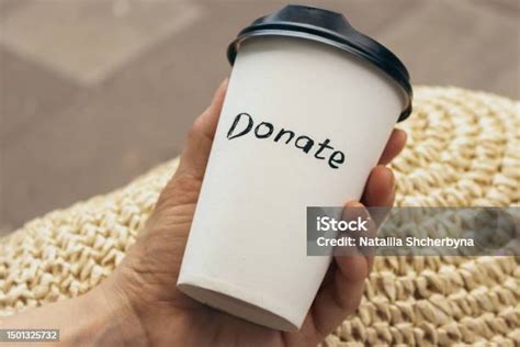 텍스트가 있는 흰색 컵은 손에 기부합니다 자선 개념입니다 커피 한 잔을 들고 손을 뺏는다 종이컵에 로고를 기부하십시오 기부 개념입니다 사회 활동 개념입니다 친절과 도움