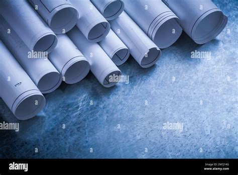 Rolls Of White Construction Drawings On Scratched Metallic Background Building And Architecture