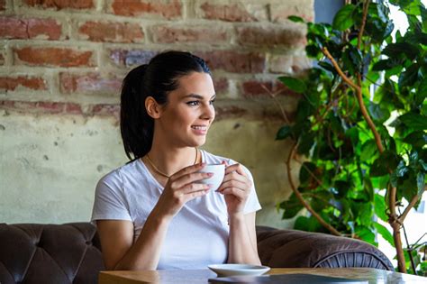커피 한 잔과 아름 다운 젊은 여자입니다 여자는 아침에 일출과 함께 신선한 커피를 즐긴다 커피 가게 아름다운 여자는 창가에 앉아 아침에 커피를 마시는 고객에 대한 스톡 사진
