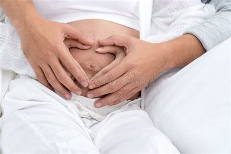 用手在怀孕的肚子上做心脏形状的夫妇 怀孕的女人和丈夫手牵手 库存照片 图片 包括有 聚会所 幸福 204435934