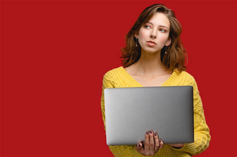 빨간 배경에 여자의 스튜디오 초상화 온라인 작업에 대 한 노트북 컴퓨터를 사용 하 여 사람 현대인과 개념 노란색 점퍼를 입고