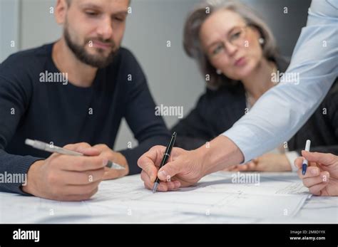 Four Colleagues Are Discussing Blueprints In A Conference Room In An Office Brainstorming Of