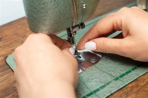 Premium Photo Seamstress Puts A Thread On A Needle In A Sewing Machine