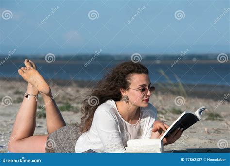 Woman With Long Curly Hair Reading A Book At The Beach Stock Image