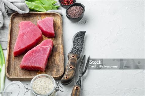 원시 참치 스테이크 신선한 붉은 참치 필레 재료 녹색 완두콩 참깨와 향신료 나무 트레이에 흰색 돌 배경에 카피 스페이스와 텍스트
