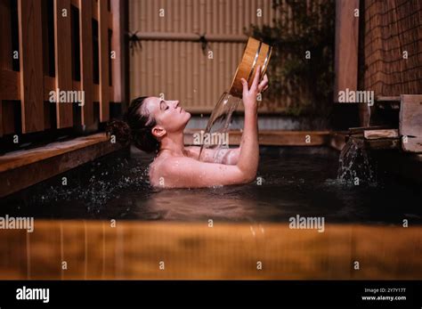 A Woman Enjoys A Peaceful Moment In An Outdoor Japanese Onsen Pouring