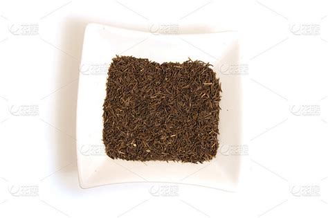 黑色孜然种子在方形的白色碗中孤立