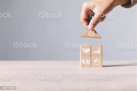 손은 사업 전략과 행동 계획에 대한 아이콘으로 나무 블록을 쌓고 있습니다 다트 보드와 화살표는 비즈니스 목표 목표를 설정합니다 목표 및 목표 비즈니스 개념 공간을 복사합니다