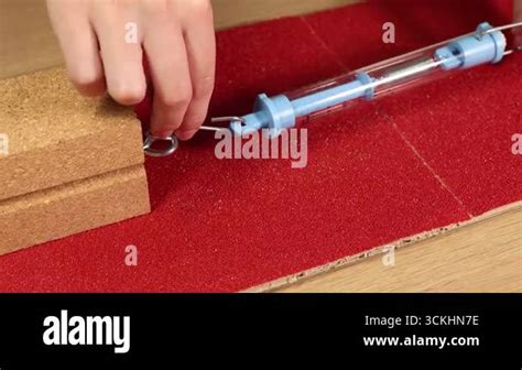 A Hand Uses A Spring Scale To Measure Friction On A Wooden Block Over Sandpaper Demonstrating