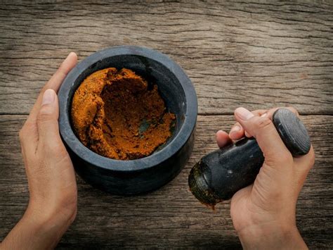 Premium Photo Cropped Image Of Hand Making Paste In Mortar And Pestle At Table