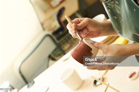 유약으로 점토 머그잔을 그리는 소녀의 클로즈업 페인트 브러시로 작업장에서 도자기를 색칠하는 여성 녹색 앞치마 글레이징 점토 냄비에 화가 공예에 대한 스톡 사진 및 기타