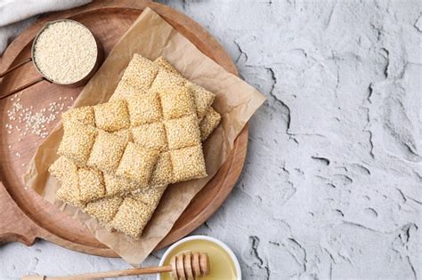 흰색 질감의 테이블에 맛있는 달콤한 코지나키 바 참깨 꿀을 담은 나무 쟁반 평평하게 놓여 있습니다 텍스트를 위한 공간 0명에