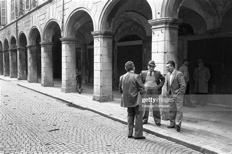 Three Men Talk Together Beside A Portico On Via Roma Busseto Italy