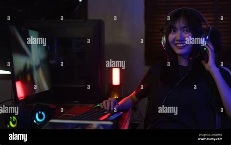 Female Cyber Hacker Gamer In Headphone Playing Games Or Hacking Programming System In Neon Light