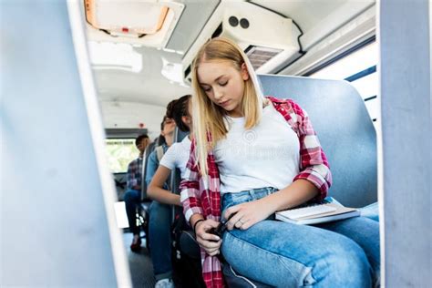 Teen Schoolgirl Riding School Bus With Classmates And Fastening Seat