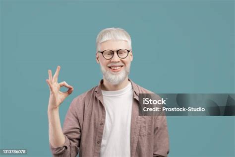 모든 것이 괜찮습니다 조이풀 알비노 남자 수행 승인 확인 제스처 와 손가락 그는 괜 찮 아 요 보여주는 블루 스튜디오 배경