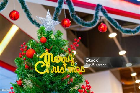 빨간 공으로 장식된 전나무 꼭대기에 메리 크리스마스 비문과 실내에 설치된 반짝이는 조명 빨간 새틴 실크 리본으로 장식된 판지 종이 상자 선물 새해 0명에 대한 스톡 사진 및