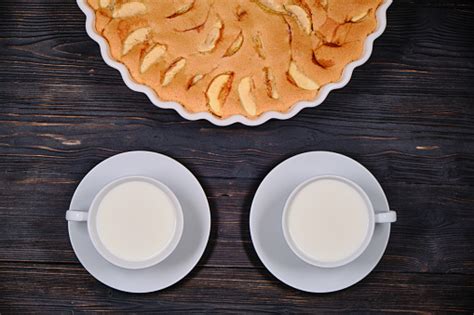 어두운 나무 배경에 잘 익은 사과의 홈 베이킹 요리와 우유에 과일 케이크 큰 사과 파이와 우유 두 컵 거품 내기에 대한 스톡
