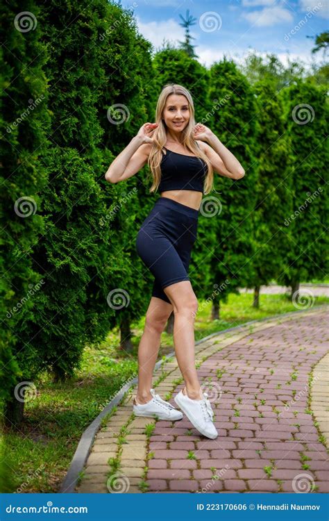 Young Beautiful Sporty Blonde Woman In A Black T Shirt And In Black