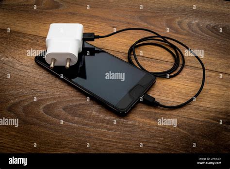 Mobile Phone Off With Disconnected Charger With Wooden Background Stock