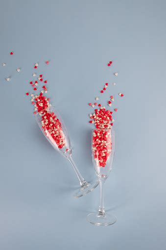 빨간 하트 모양의 설탕 사탕의 스플래시와 두 개의 샴페인 안경 파란색 배경 위에 발렌타인 데이 기념일 또는 결혼 축하 개념입니다 플랫 레이 맨 위 보기 공간을 복사합니다
