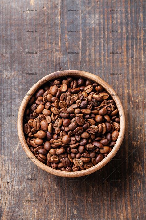 عکس دانه های قهوه در کاسه سرامیکی در پس زمینه چوبی عکس با کیفیت و