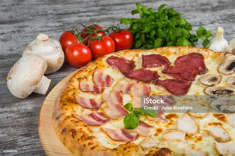 밝은 나무 배경에 로즈마리와 향신료와 네 부분으로 피자 녹색 바질과 신선한 야채를 배경으로 한 이탈리아 피자 0명에 대한 스톡
