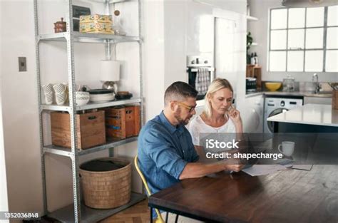Shot Of A Couple Going Through Documents Together While Using Their