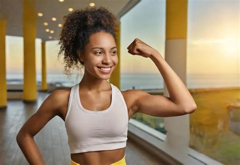 A Woman Is Smiling And Flexing Her Arm In A Gym Premium Ai Generated