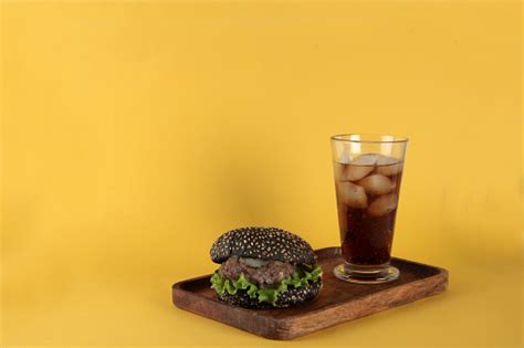 나무 접시에 검은 햄버거와 노란색 배경에 고립 된 얼음 콜라 한 잔 0명에 대한 스톡 사진 및 기타 이미지 0명 건강에